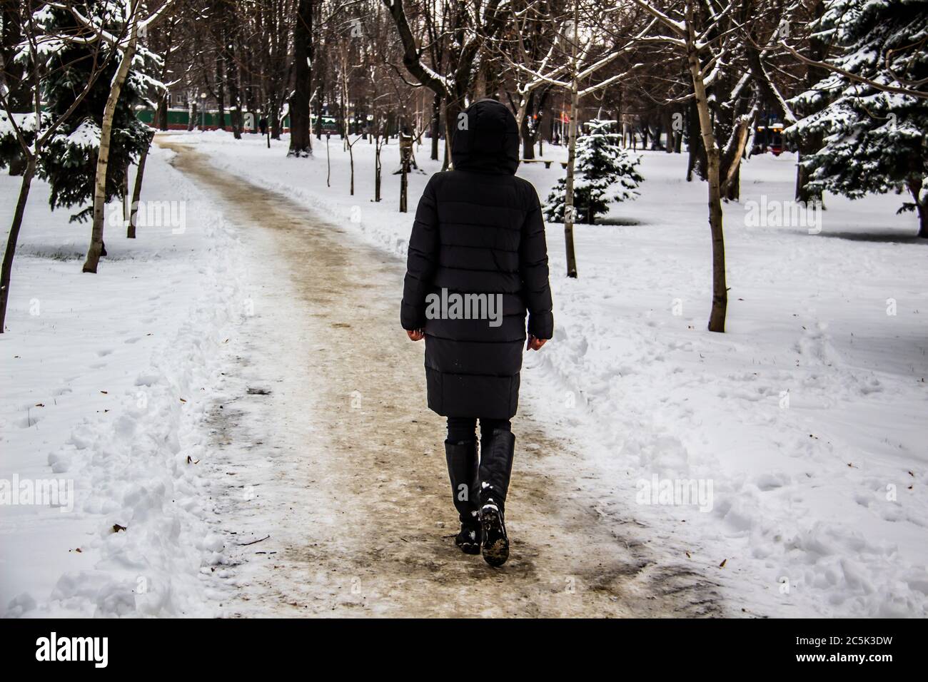 Une fille en manteau noir marche le long de la route. Silhouette d'une ...