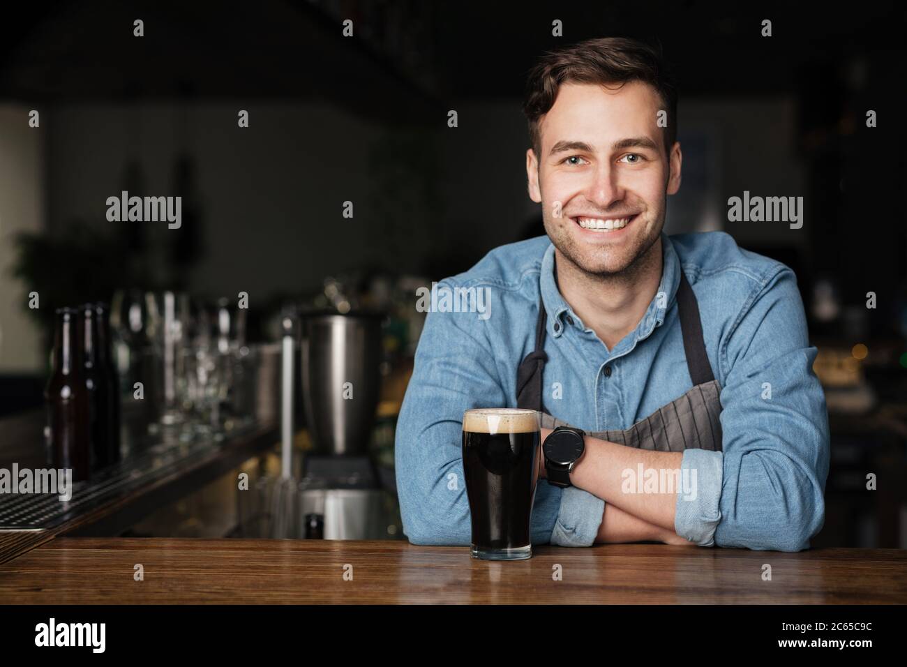 Potins avec le client dans un pub avec un verre de bière. Barman souriant et sympathique, bras ...