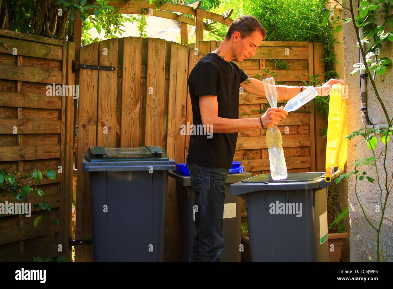 Personne effectuant un tri sélectif des déchets ménagers dans des bacs ...