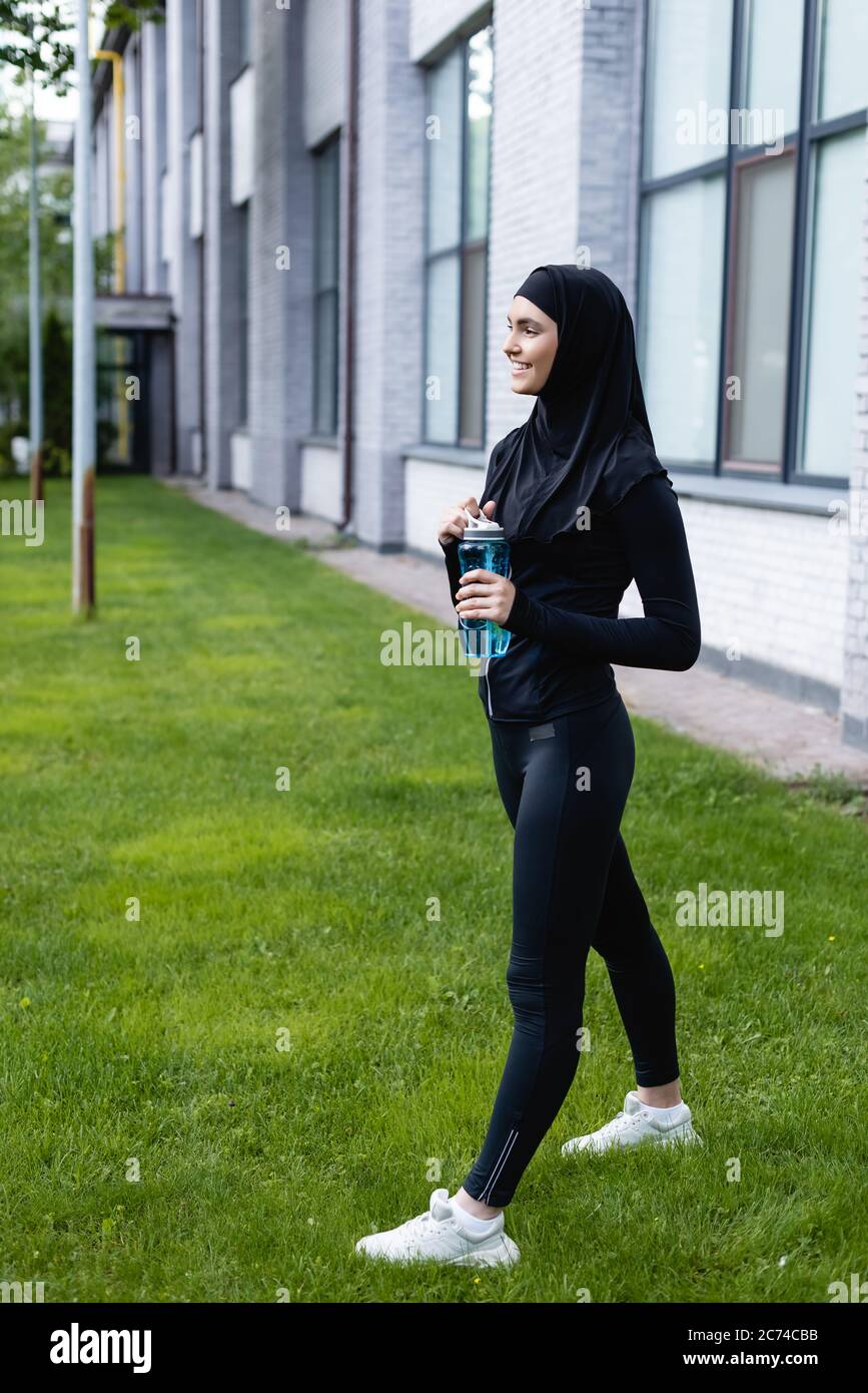 joyeuse sportive musulmane dans hijab tenant une bouteille de sport ... joyeuse sportive musulmane dans hijab tenant une bouteille de sport ...