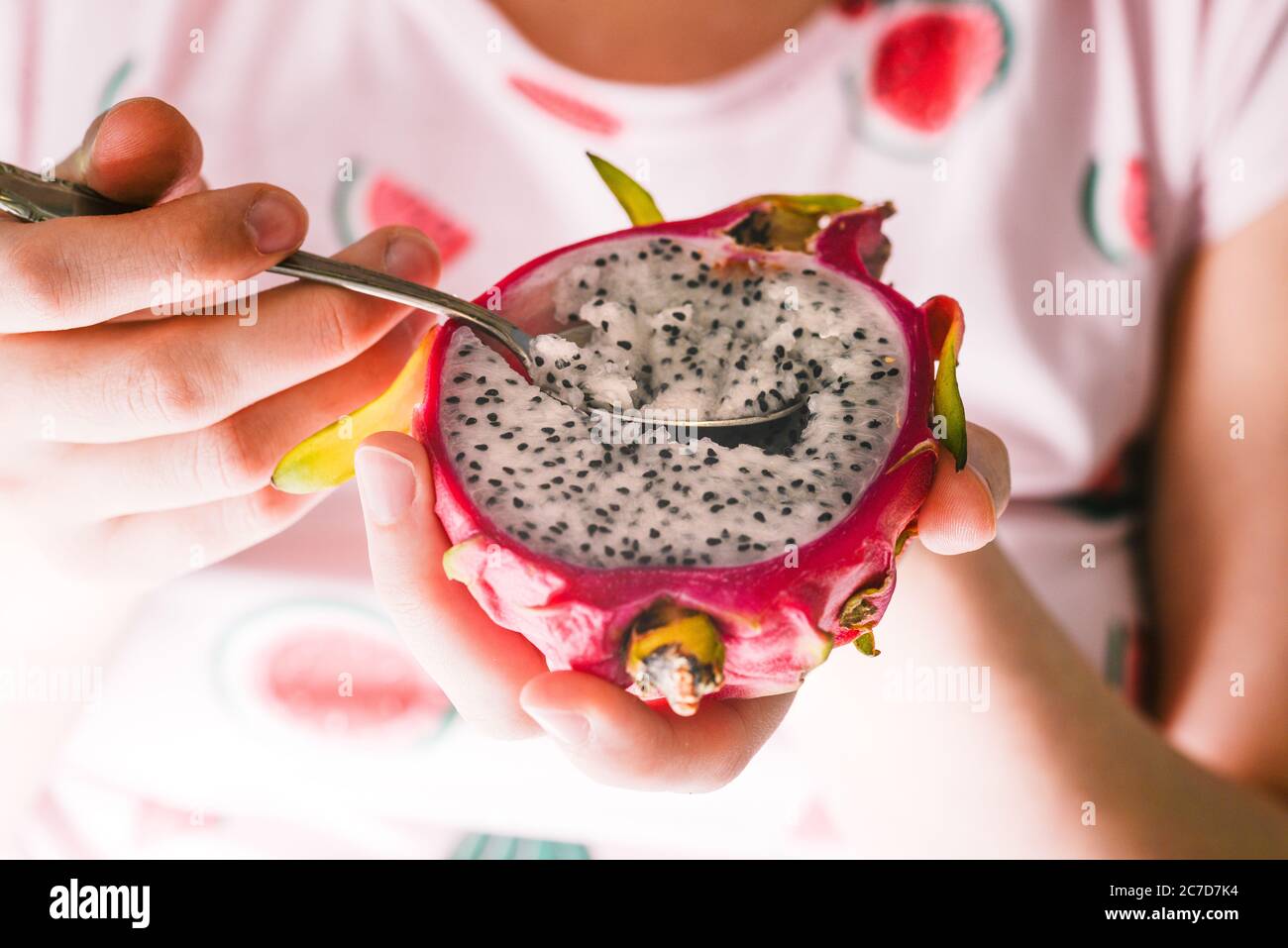 Une femme mange avec une cuillère en fer le fruit tropical pitaya ...