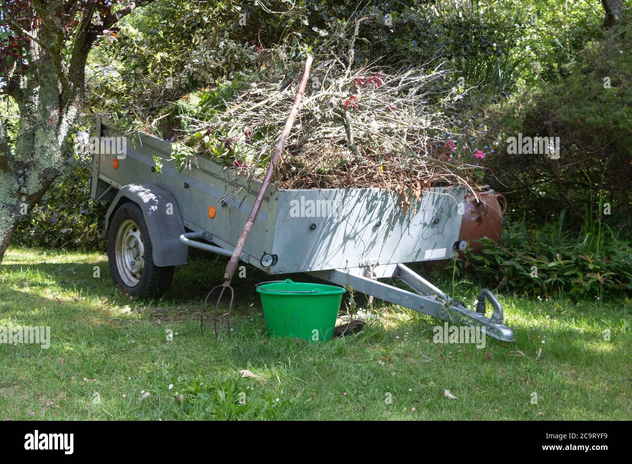 Remorque pleine de déchets de jardin, fourche et seau après le ...