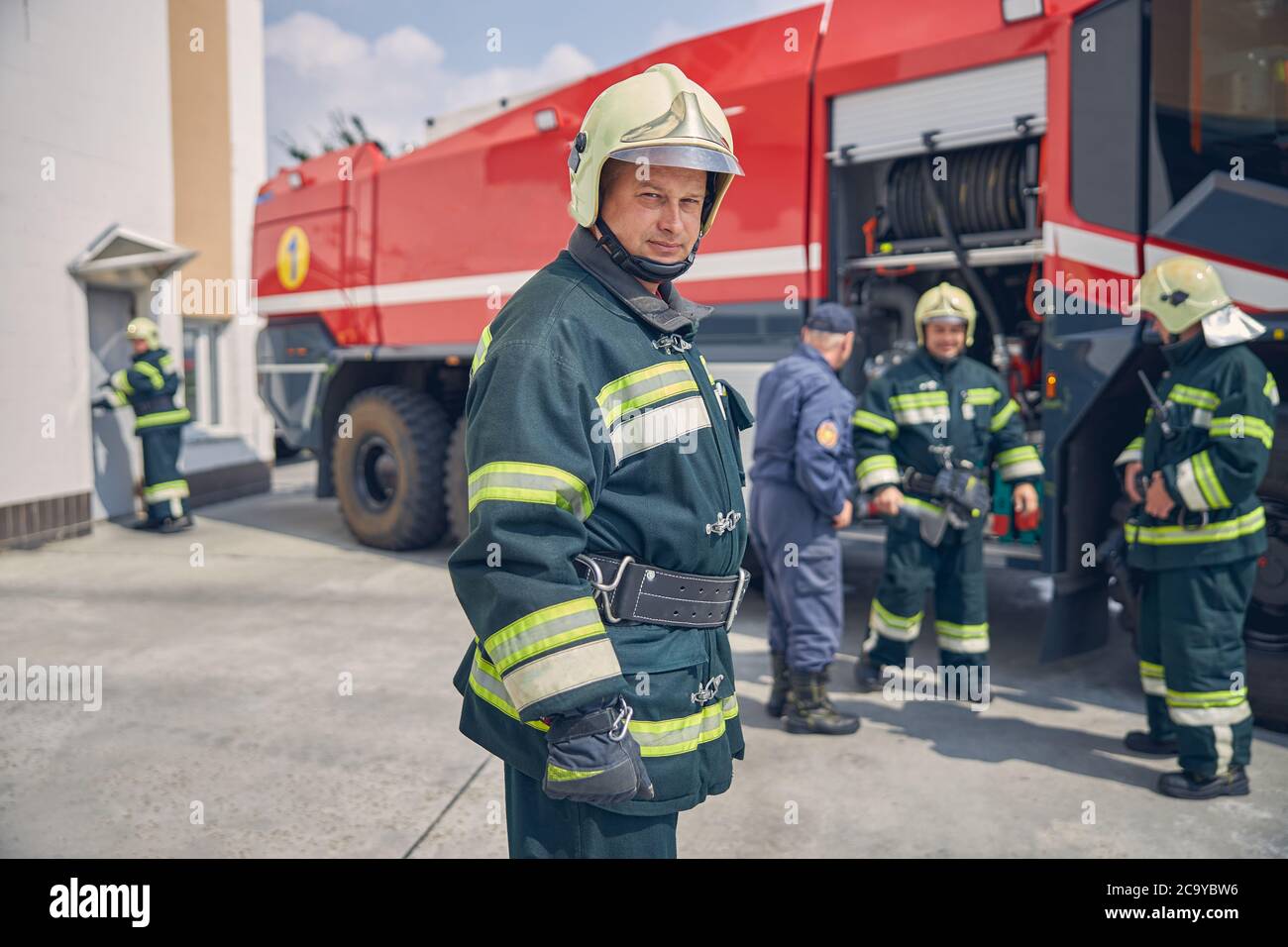 Une équipe de pompiers heureux apprend sur les camions à la caserne de ...