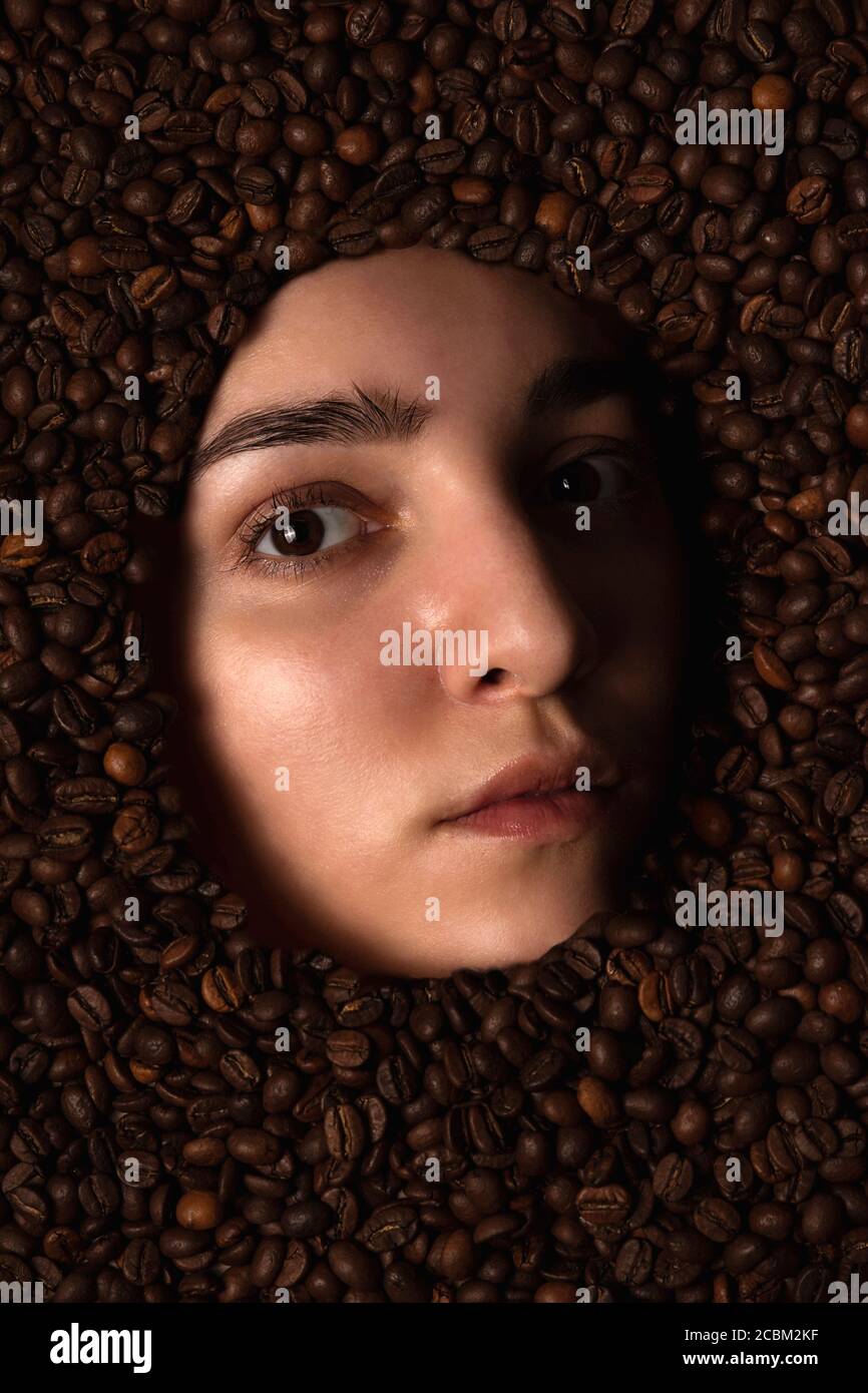 Magnifique visage féminin parmi la texture des grains de café Photo ...