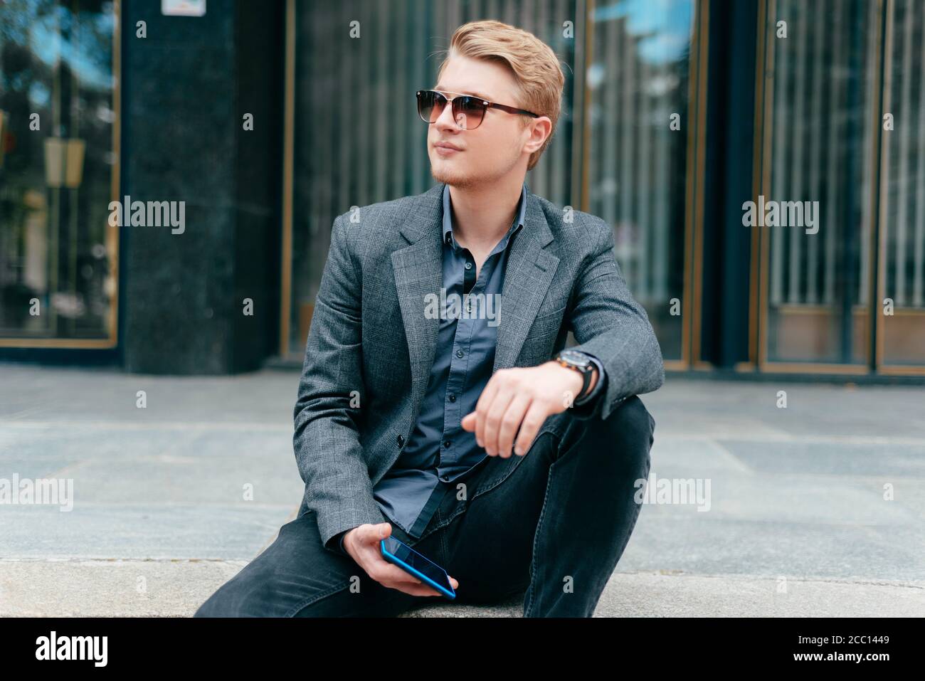 Portrait d'un jeune homme en costume assis dans un escalier en ville et ...
