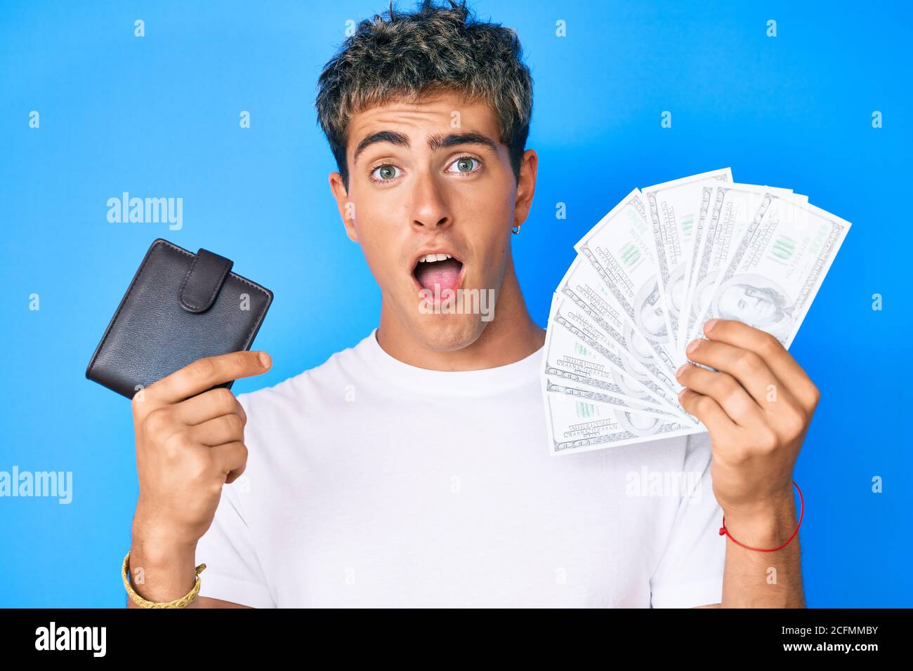 Jeune homme beau tenant des billets de portefeuille et de dollars ...