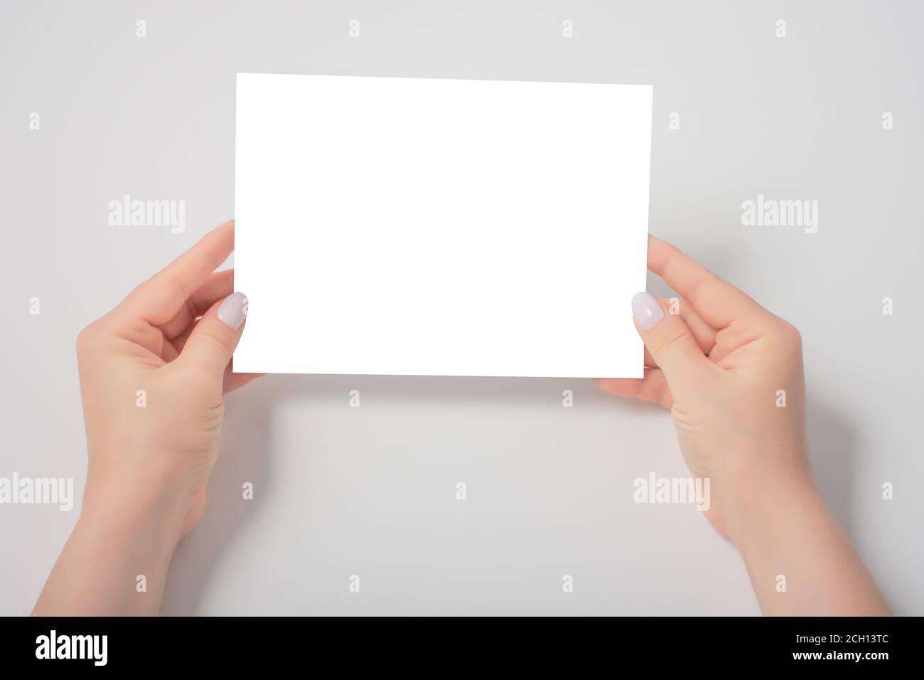 Mains des femmes tenant une feuille de papier vierge, sur fond gris ...