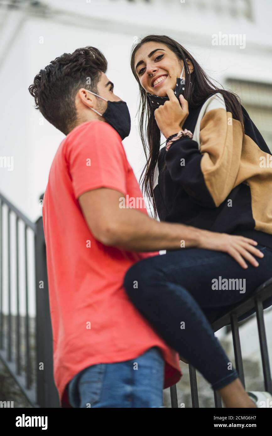 Jeune couple avec un masque de protection sur un escalier souriant et ...