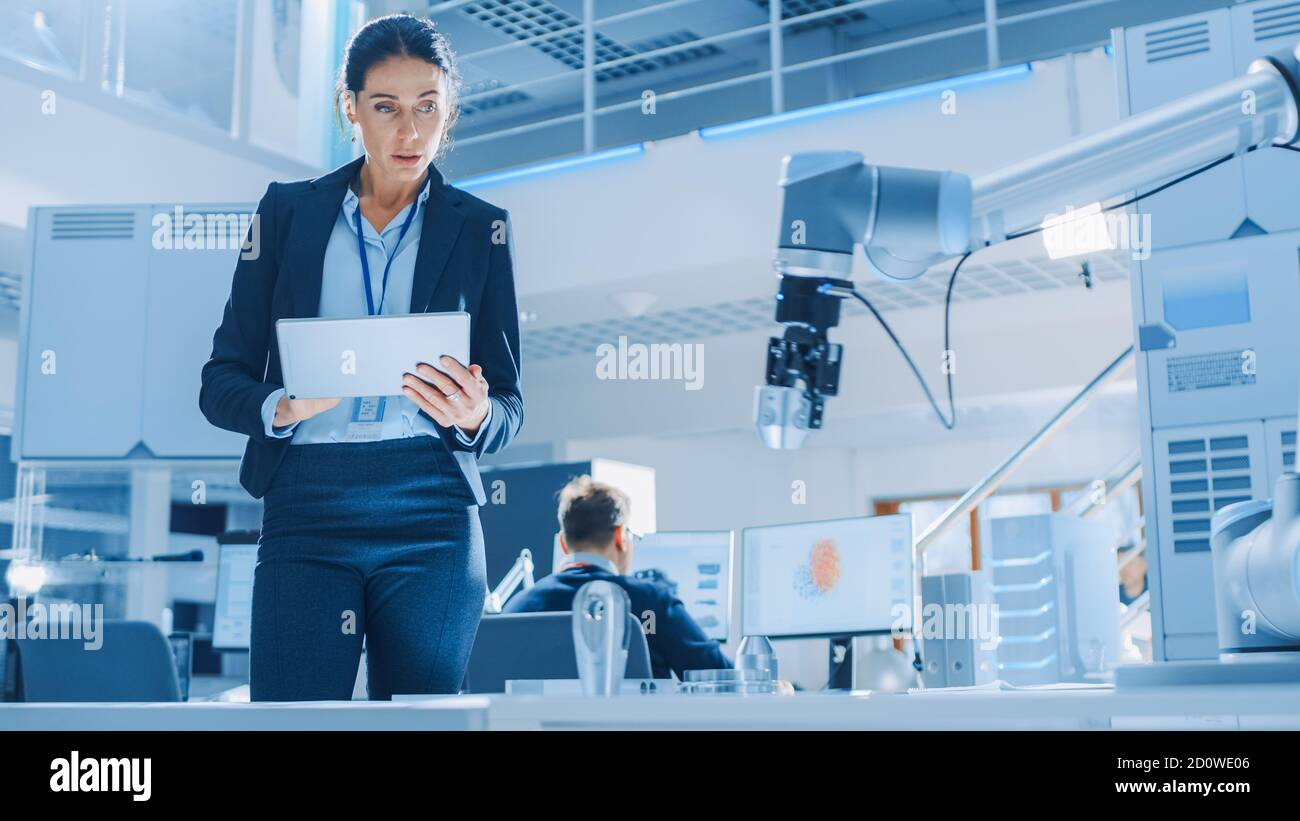 L'ingénieure en robotique industrielle féminine utilise une tablette ...