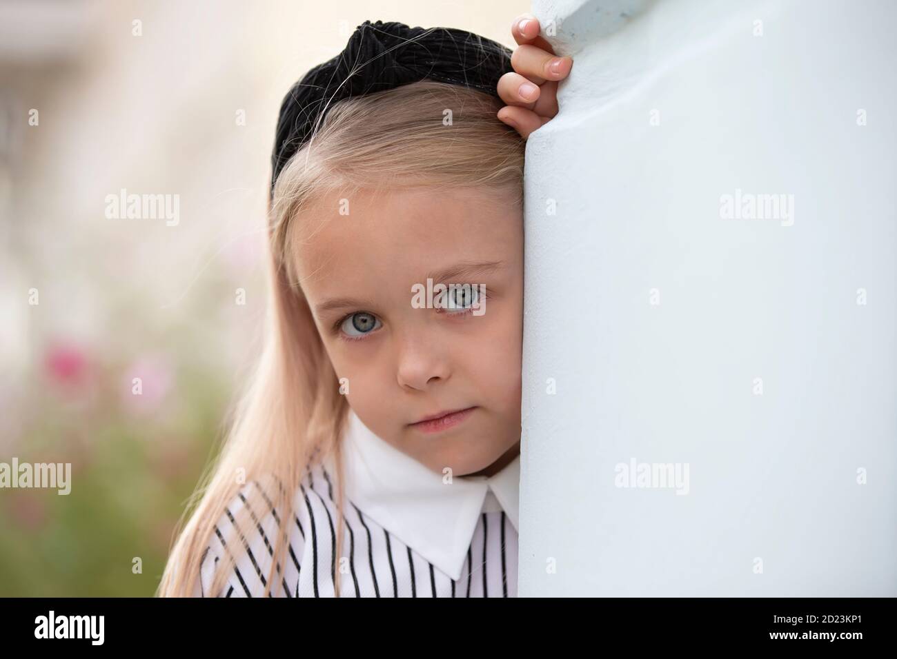 Le triste visage d'une belle petite fille qui peeks dehors de derrière le mur Photo Stock - Alamy