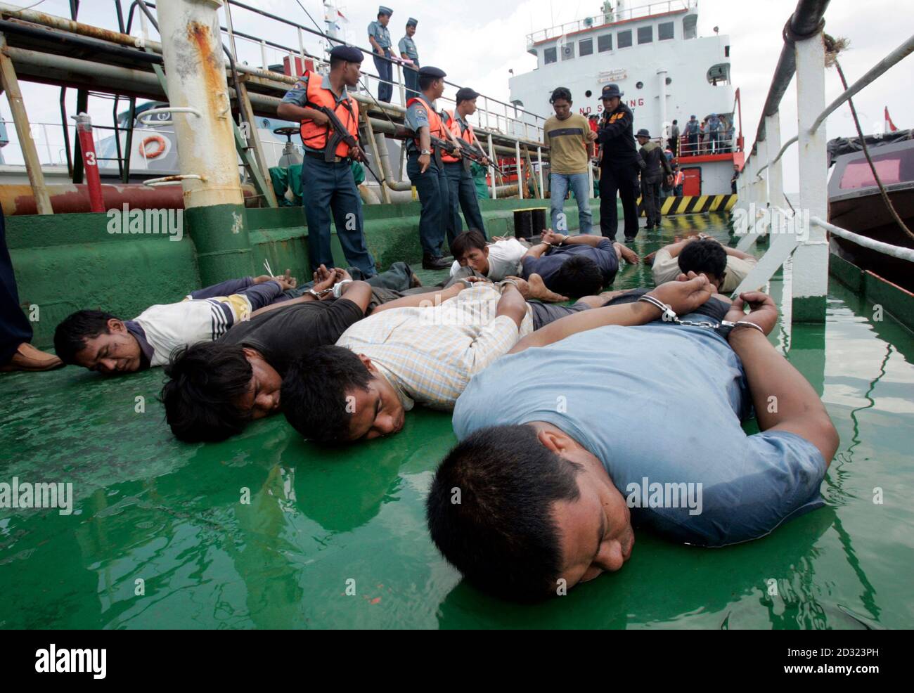 Indonesia navy personnel hold their rifles as a group of pirates lie on ...