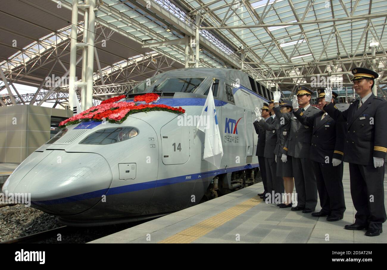 A group of train crew wave as the Korean Train Express (KTX) departs ...