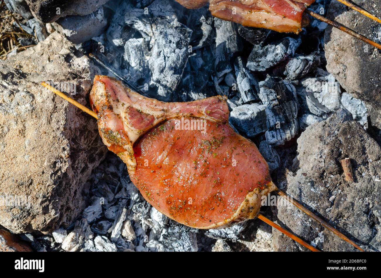 L'entrecote de porc est grillée sur des charbons dans la forêt. Deux ...