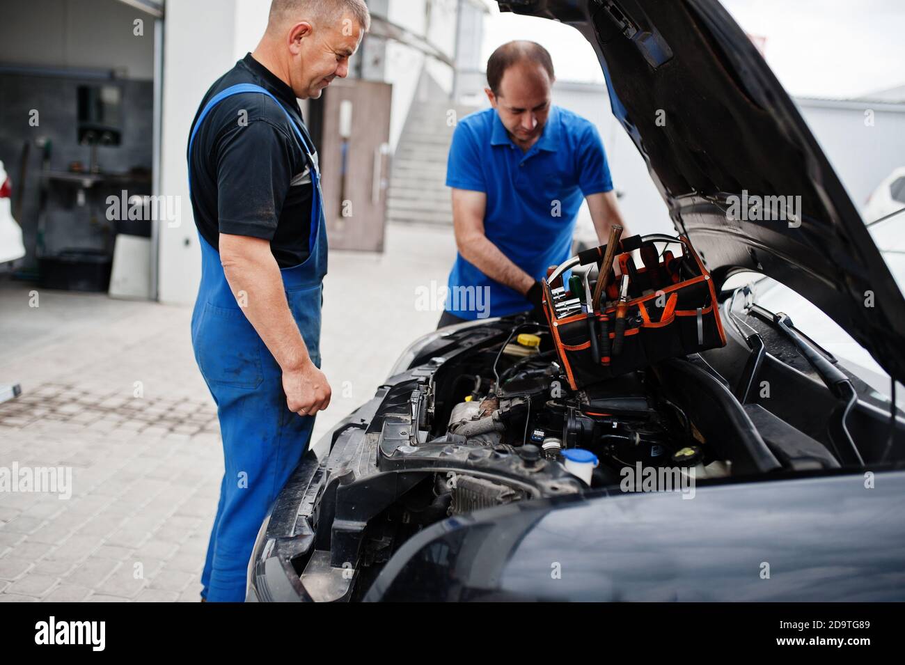 Thème de réparation et d'entretien de voiture. Deux mécaniciens en uniforme travaillant en ...