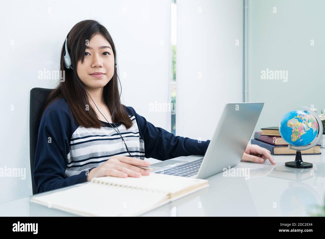 Jeune étudiante assise dans le salon et apprenant en ligne Utilisation de l'ordinateur portable ...