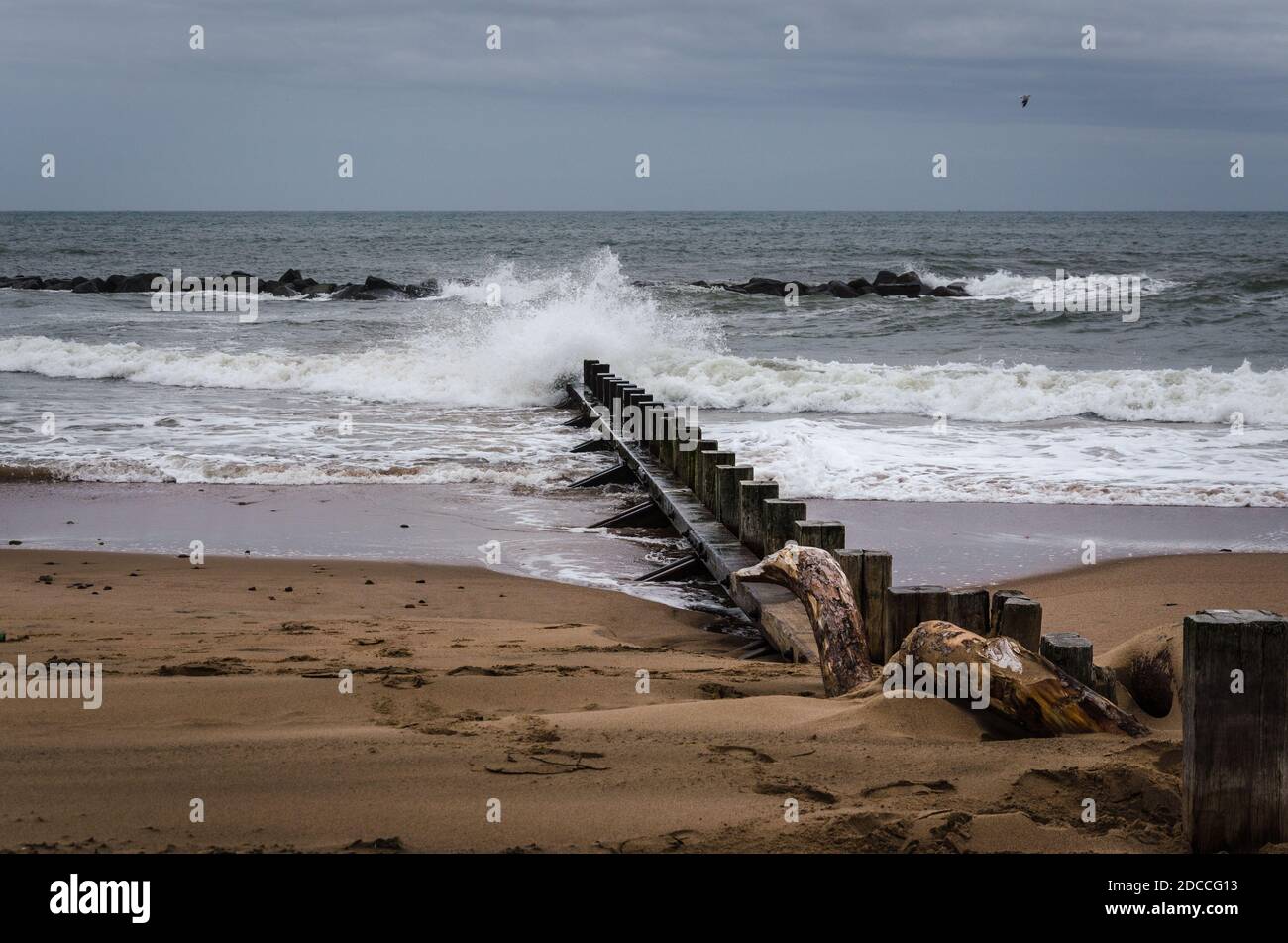 Vagues s'écrasant sur les défenses de marée sur la plage de la ville d ...