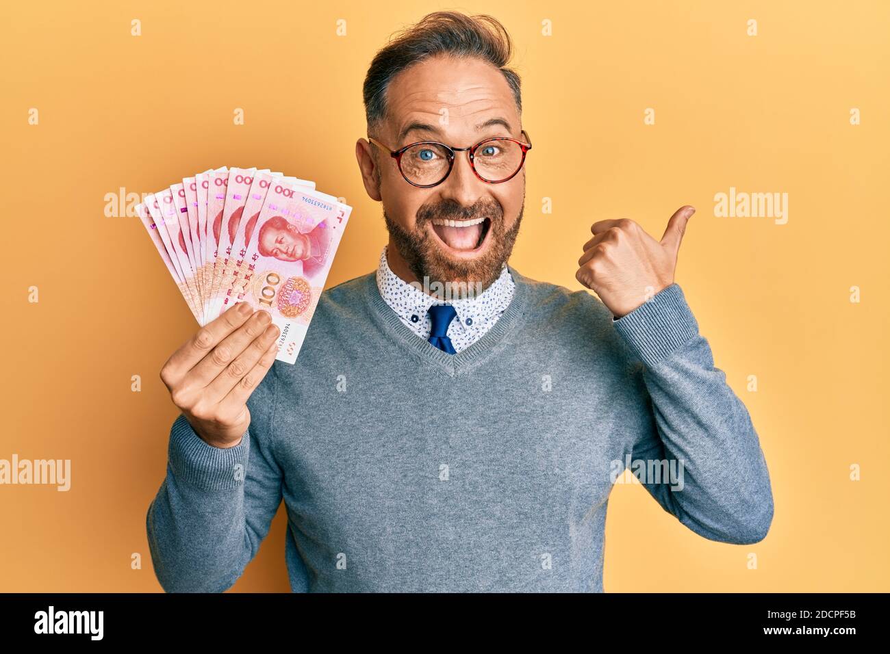 Beau homme d'âge moyen détenant 100 yuan de billets chinois pointant le ...