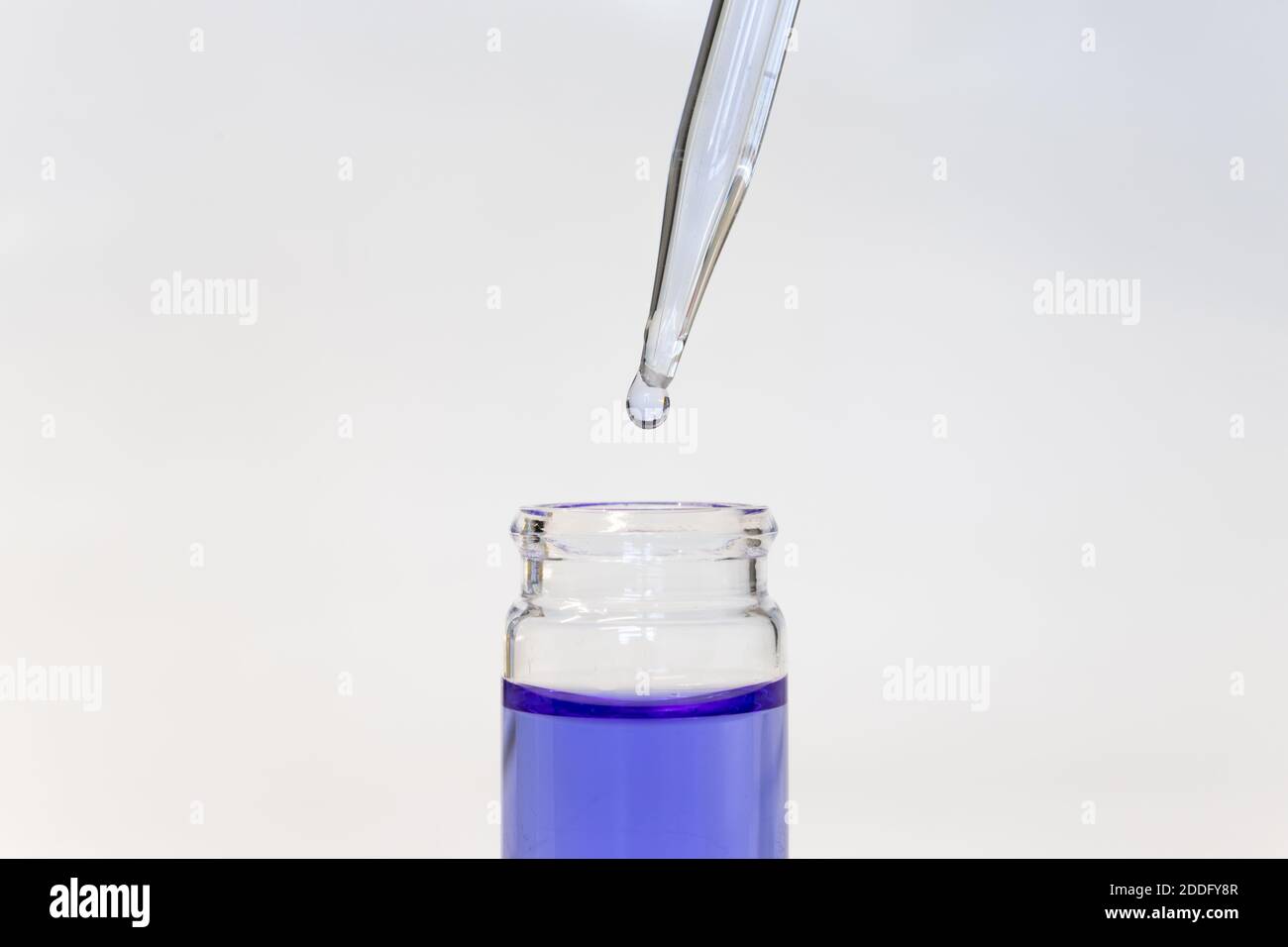 Une solution chimique violette et une pipette sur fond blanc. Chimie ...