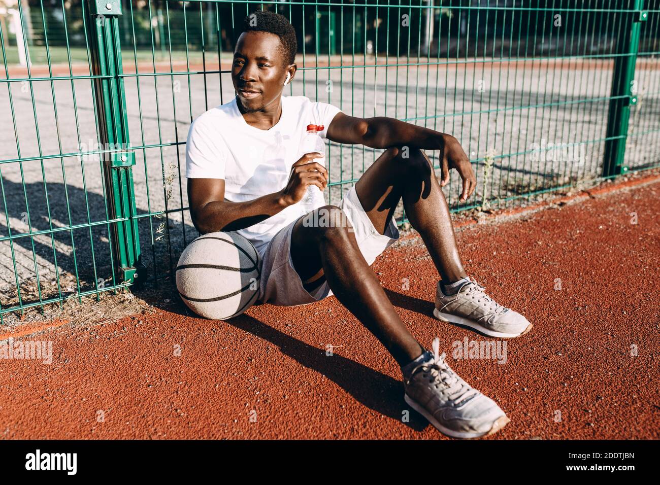 Un afro-américain fort repose après un entraînement avec un bouteille d ...