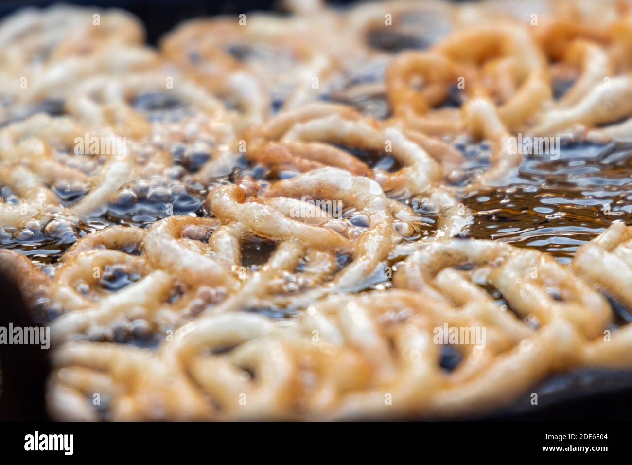 Faire frire de la pâte Jalebi dans de l'huile. La pâte rouge et orange ...