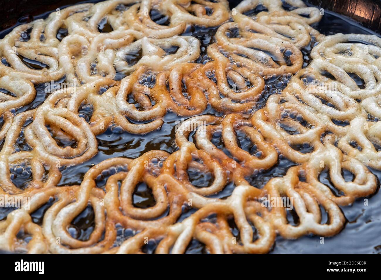 Faire frire de la pâte Jalebi dans de l'huile. La pâte rouge et orange ...