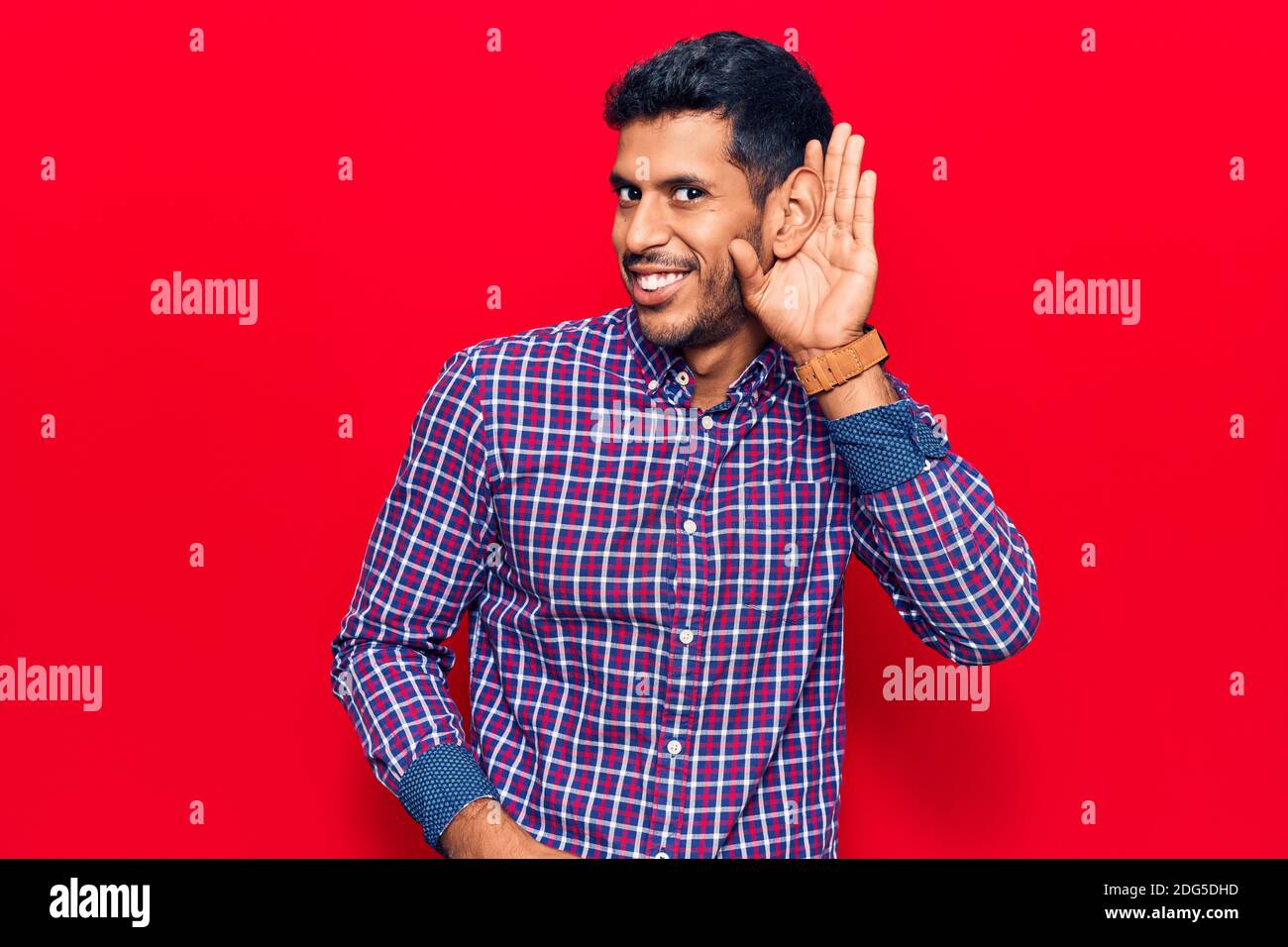 Jeune latino portant des vêtements décontractés souriant avec la main ...