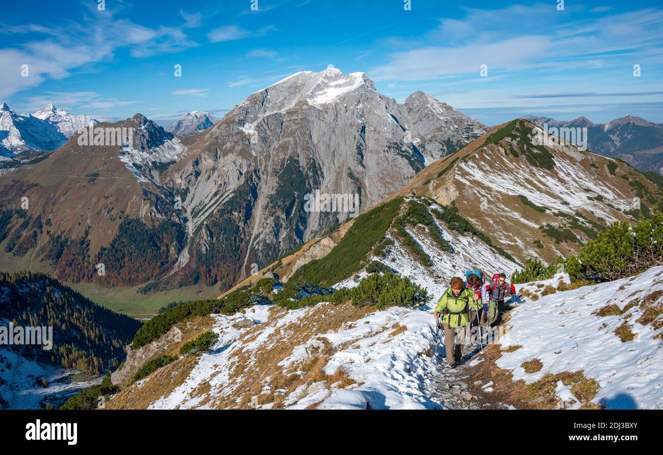 Trois randonneurs sur un sentier de randonnée avec neige en automne ...