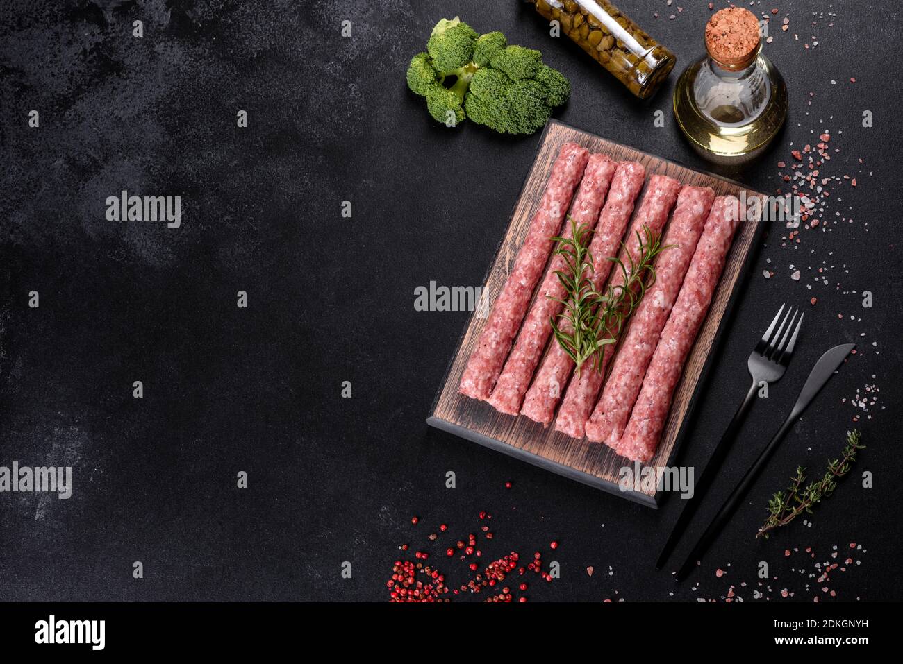 Saucisses de porc fraîches et crues aux épices sur une coupe de bois montez sur une table en ...