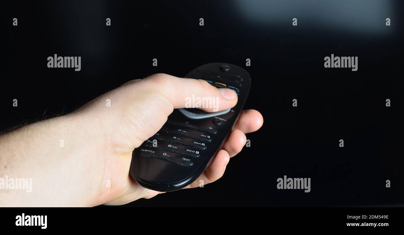 Une main mâle avec une télécommande de téléviseur s'allume Le ...