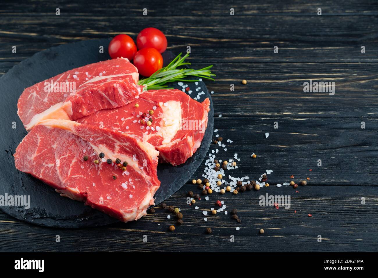 Trois morceaux de boeuf cru juteux au romarin sur une pierre à découper ... Trois morceaux de boeuf cru juteux au romarin sur une pierre à découper ...
