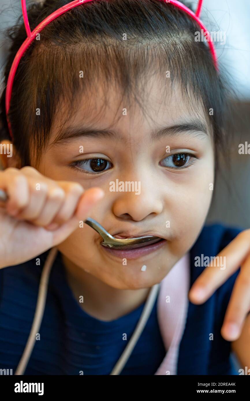 Enfant asiatique femelle tout en mangeant du riz avec une cuillère. L ...
