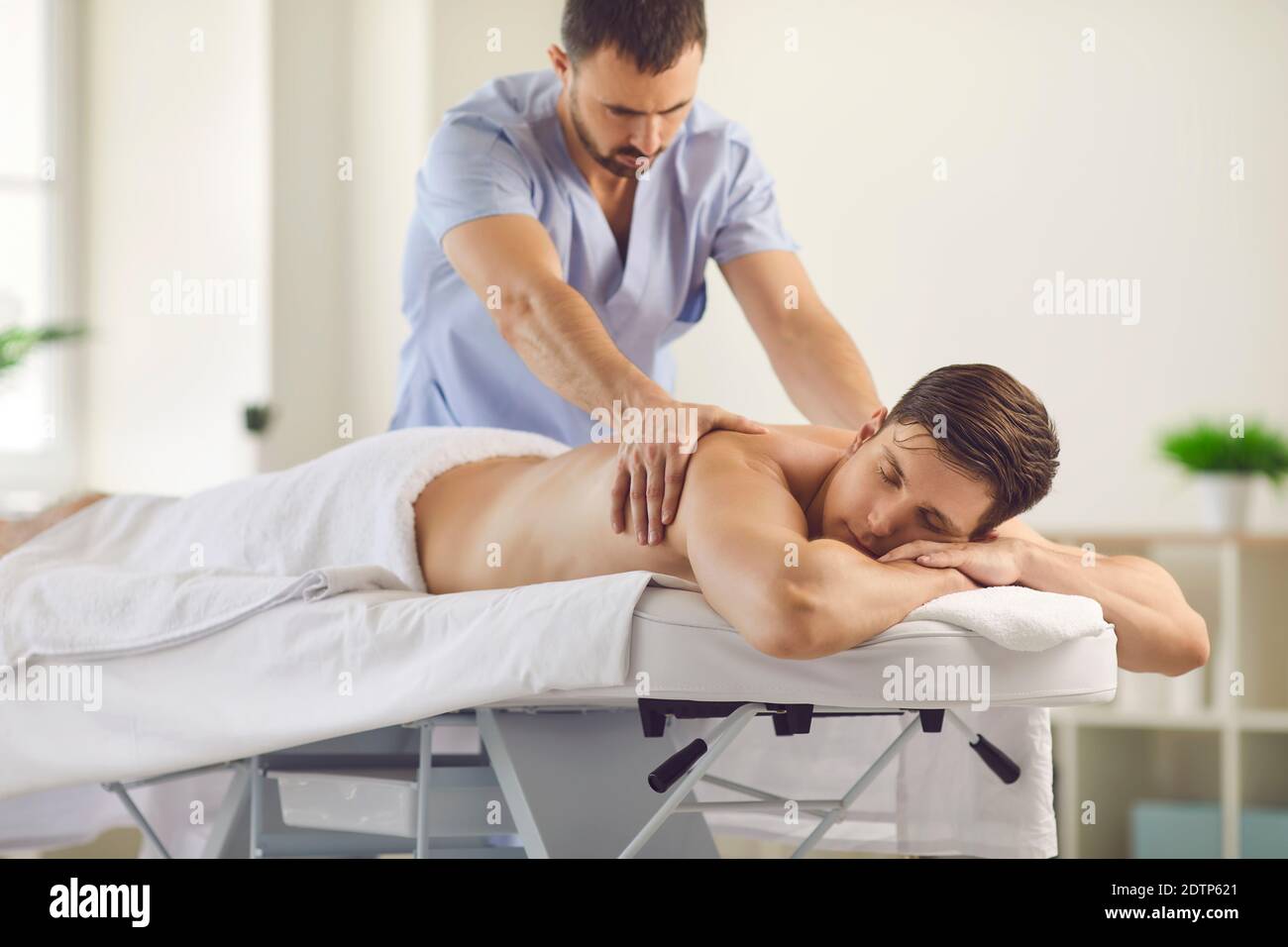 Un jeune homme se fait un massage relaxant du corps par un masseur ...