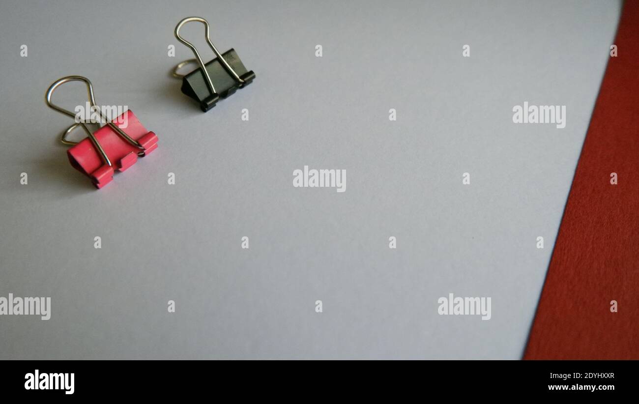 Un gros plan de trombones de reliure rouge et noir sur un morceau de ...