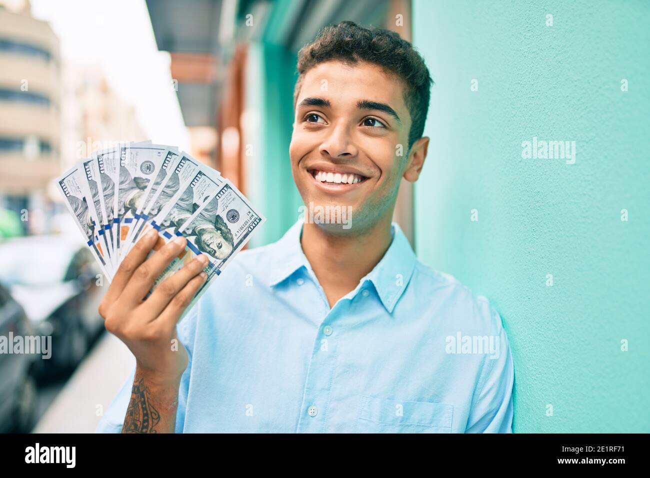 Un jeune latino souriant se réjouit de tenir des billets de banque en ...