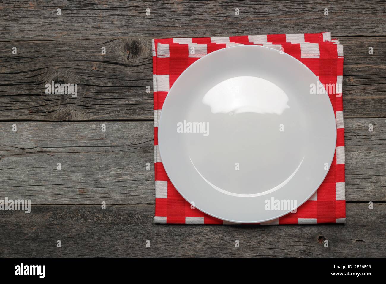 Assiette en porcelaine blanche et serviette à carreaux rouges sur une ...