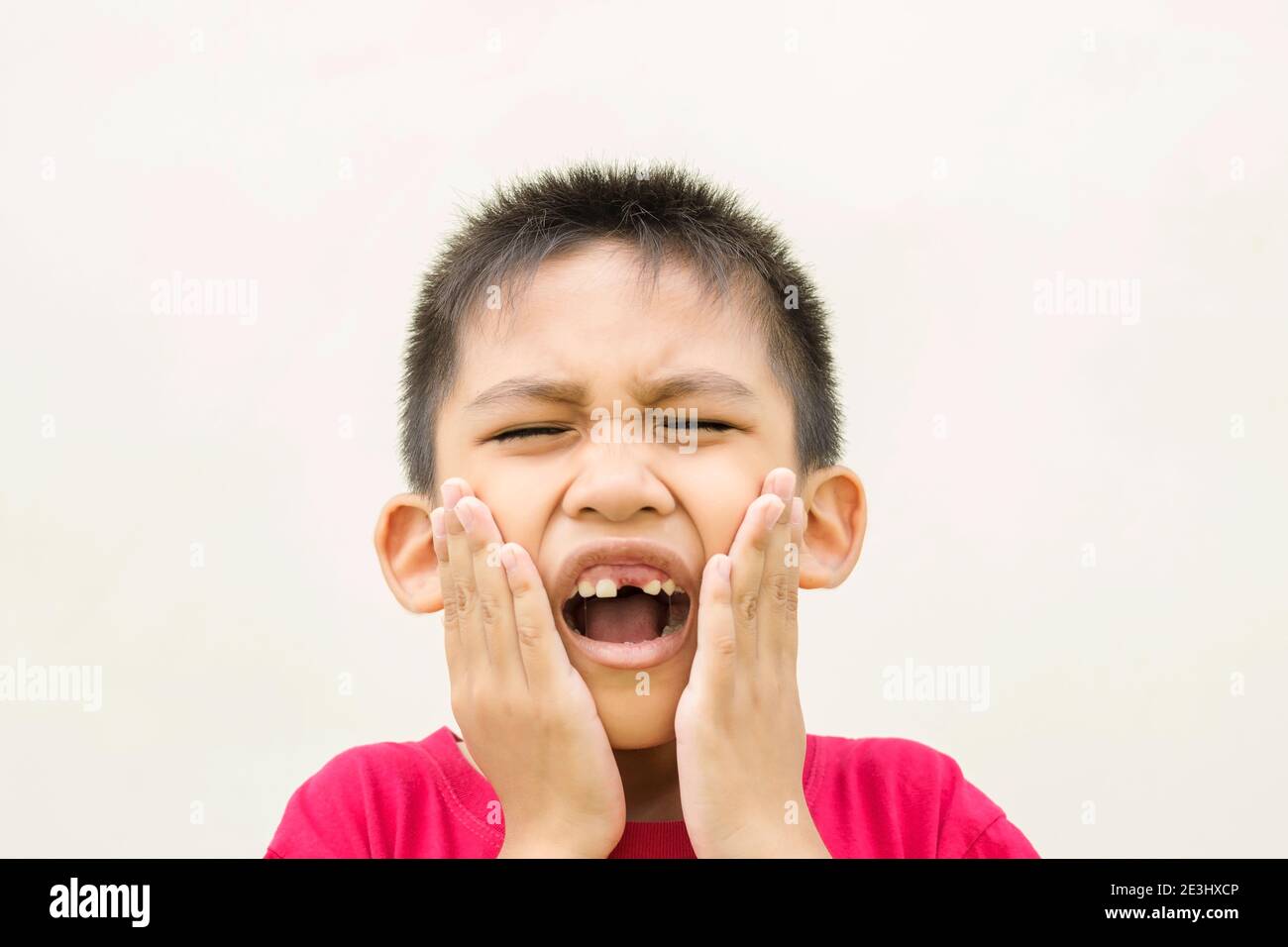 Le garçon tient sa main sur sa joue et son visage rouge avec la douleur ...