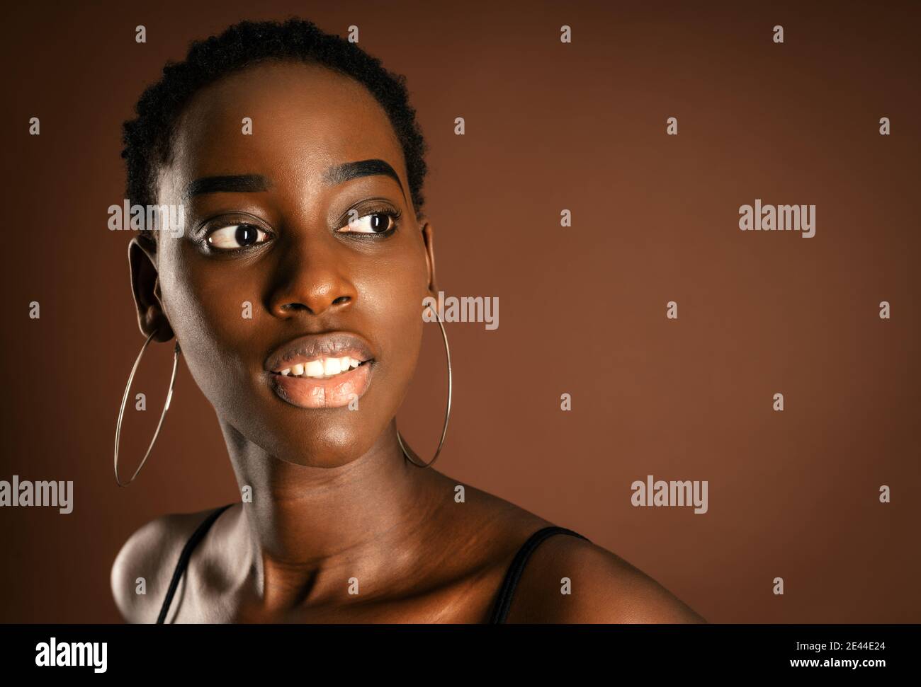 Femme noire mince avec des cheveux courts debout sur fond marron Photo ... Femme noire mince avec des cheveux courts debout sur fond marron Photo ...