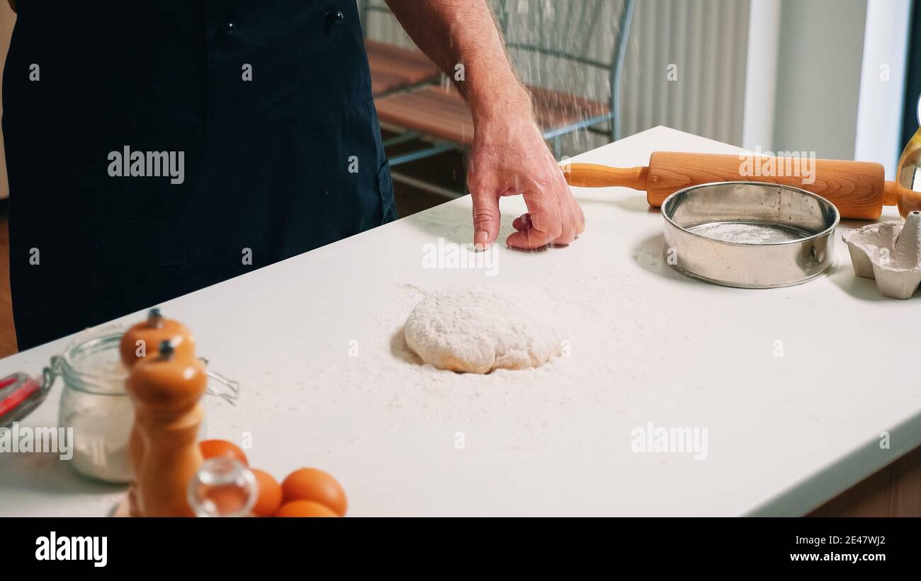 Gros plan du boulanger à la retraite en versant de la farine de blé sur ...