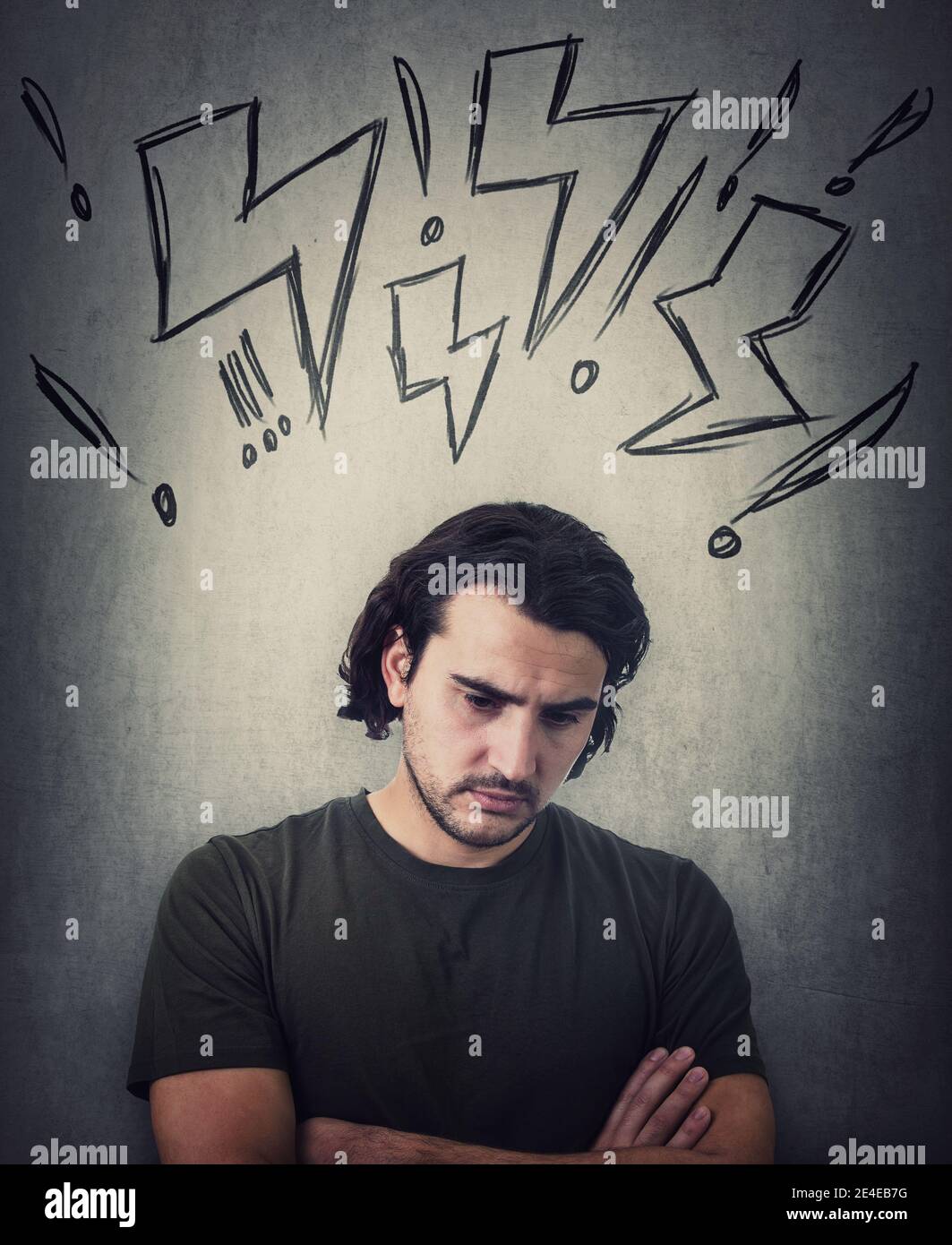 L'homme agacé fait une expression faciale mécontentée, les bras croisés ...