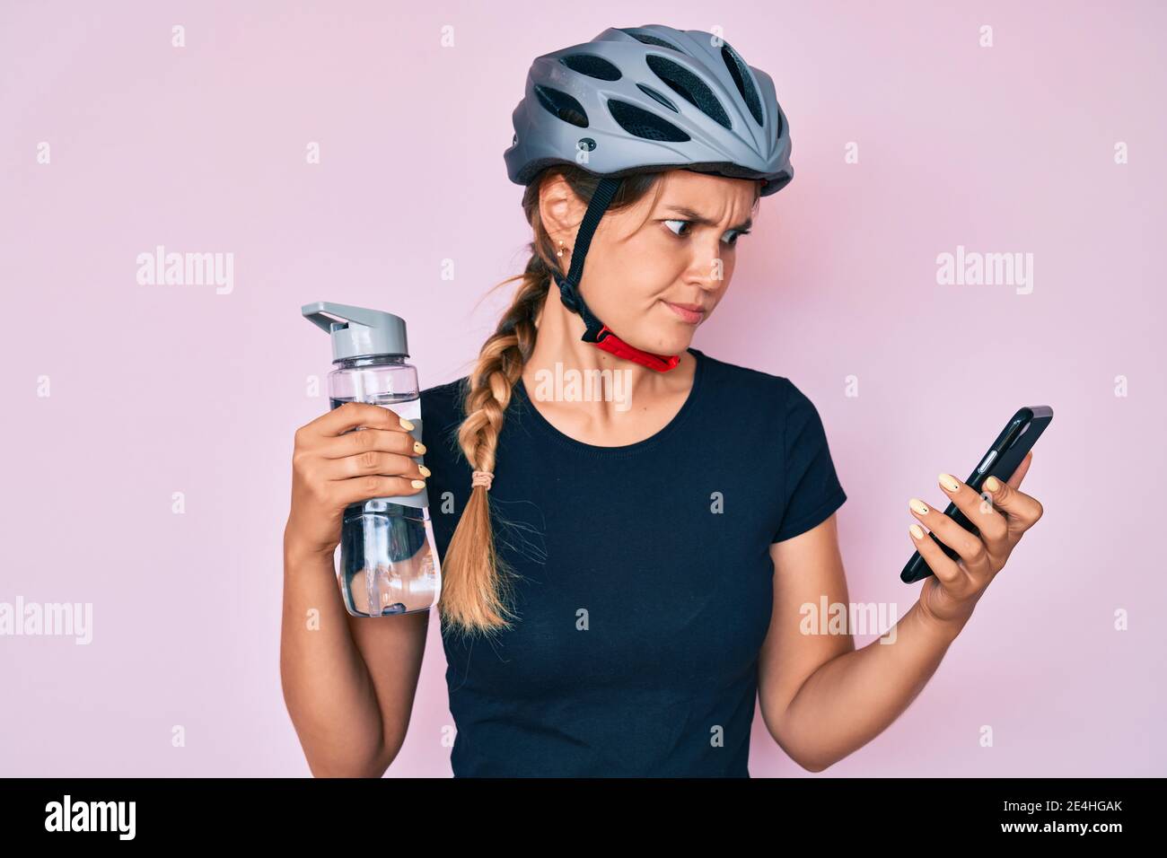 Belle femme caucasienne portant un casque de vélo regardant smartphone ...