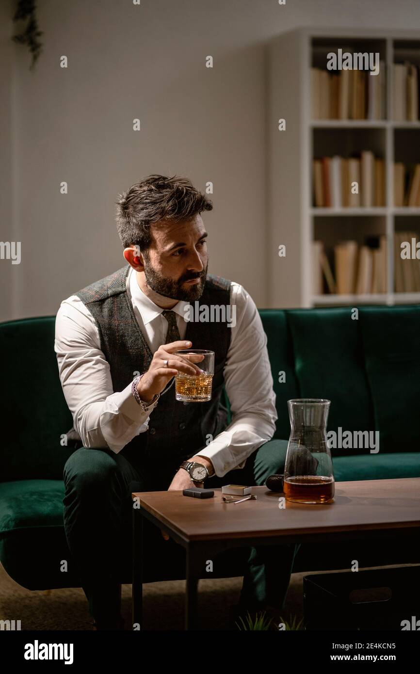 Portrait d'un homme bien habillé qui boit du whisky dans le salon Photo ...