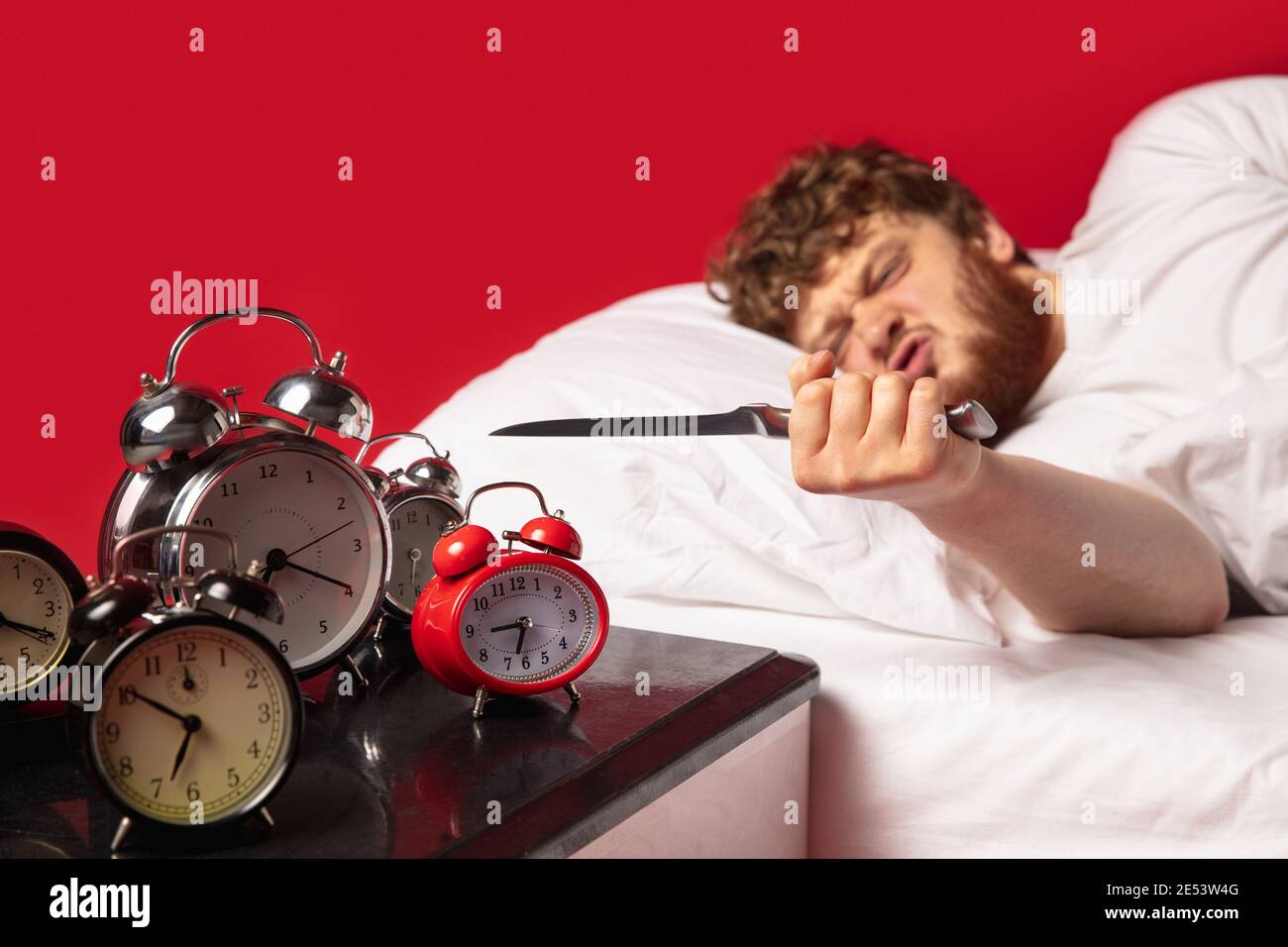 Lhomme Se Réveille Sur Son Lit Sur Fond Rouge Et Il Est Fou Des