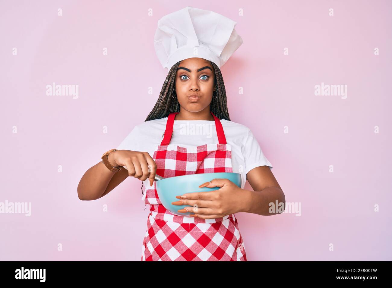 Jeune femme afro-américaine avec des braïdes cuisant à l'aide d'un ...