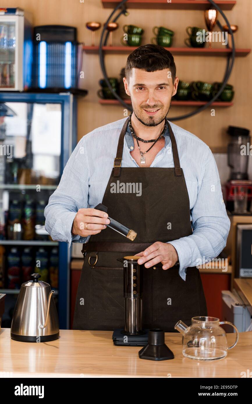 Café Aeropress et un beau barista barbu dans le café. Barisa cuisez du café savoureux en ...
