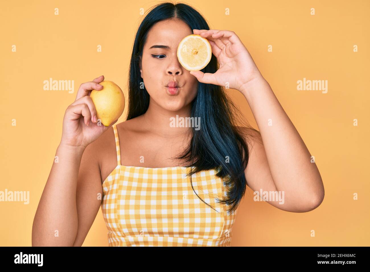 Jeune belle fille asiatique tenant le citron faisant le visage de ...