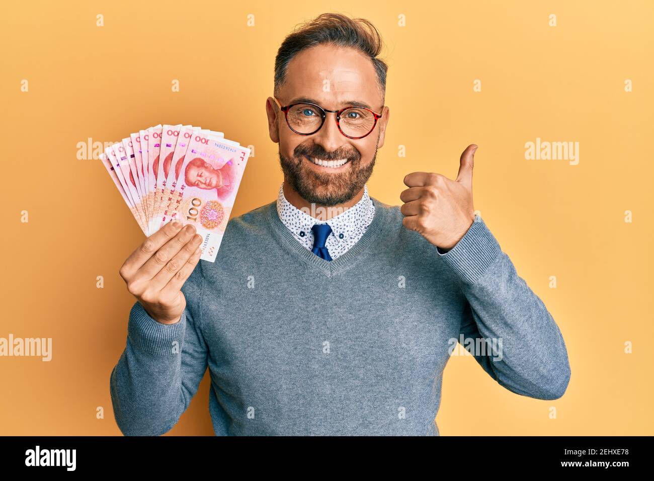 Beau homme d'âge moyen détenant 100 yuan de billets chinois souriant ...