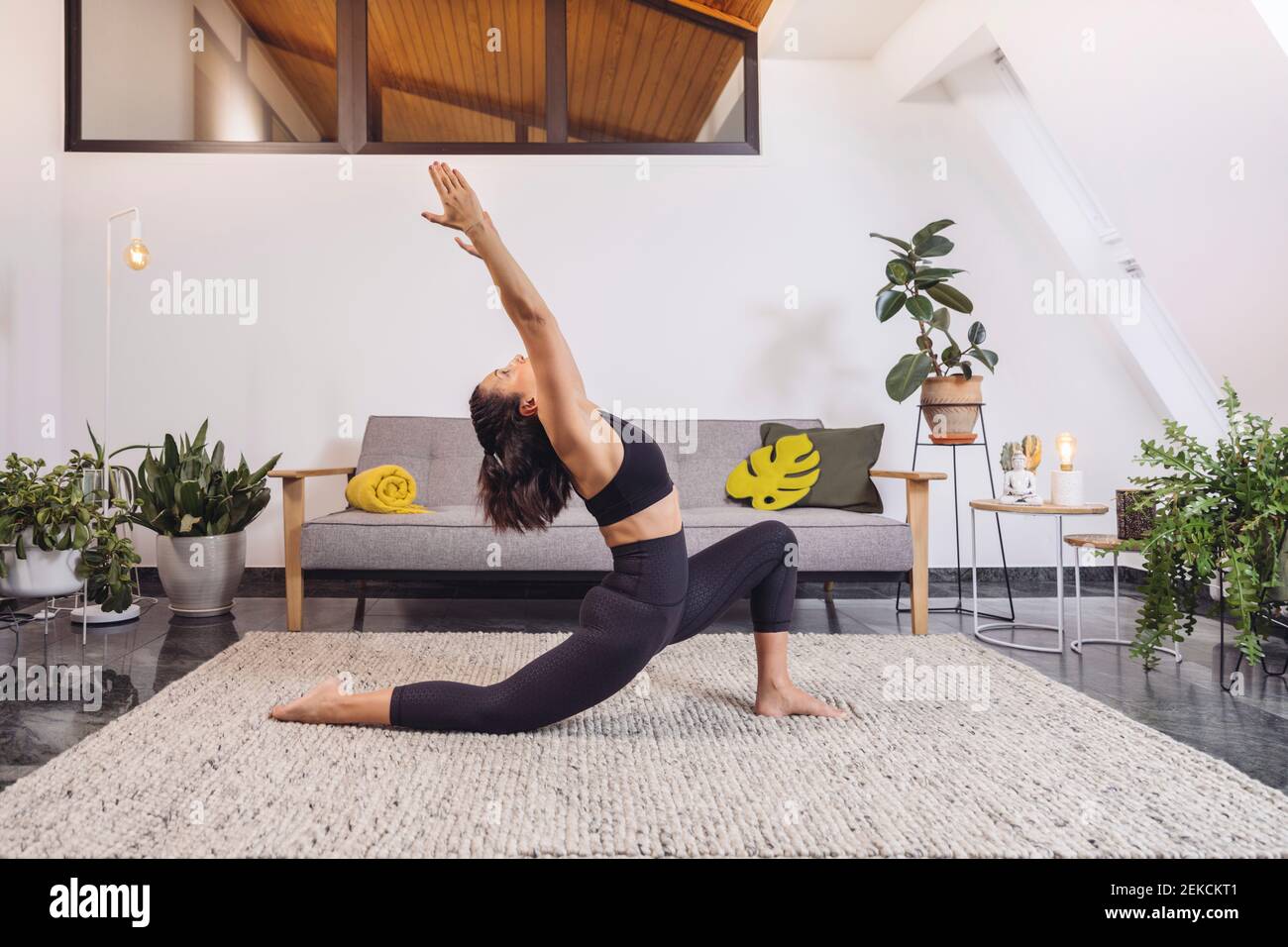 Femme pratiquant le yoga pose contre le canapé dans le salon à accueil Photo Stock - Alamy