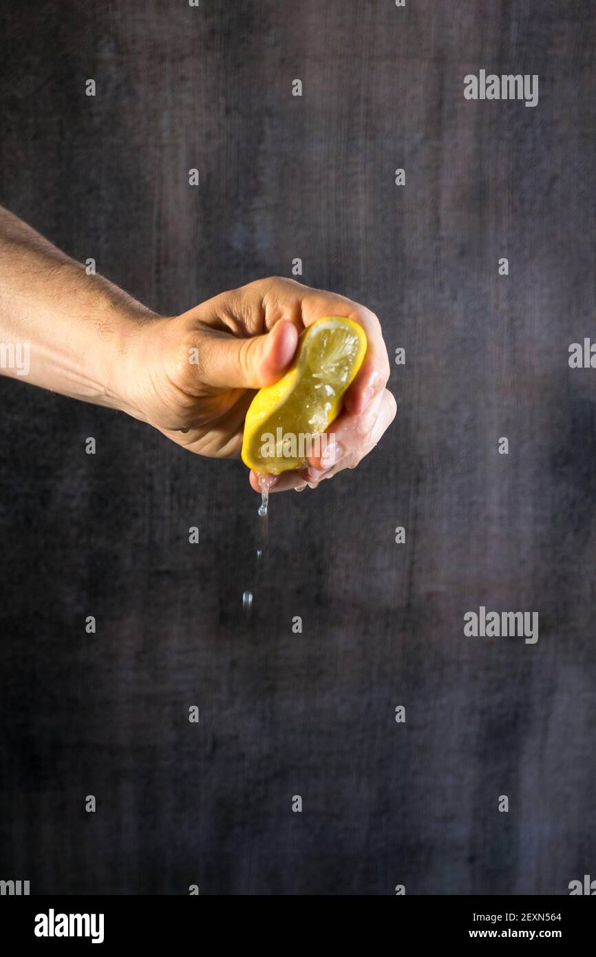 Une main pinçant la moitié du citron juteux dans le arrière-plan avec ...