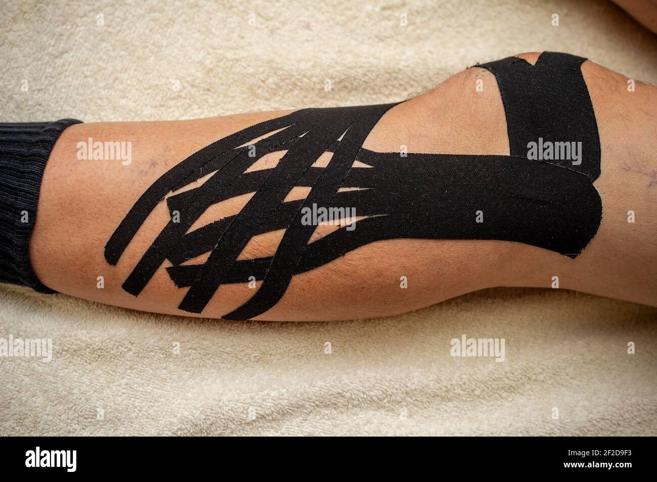 Un patient porte des rubans Kinesio, appliqués par un physiothérapeute ...