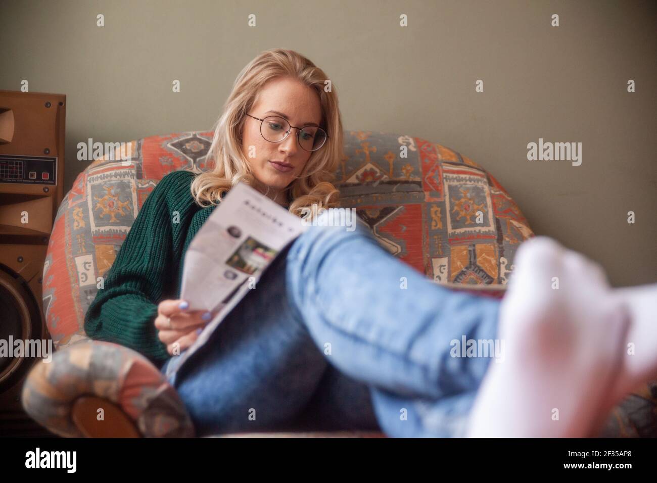 une jeune femme, en feuilleter des pages dans un magazine, assise dans ...